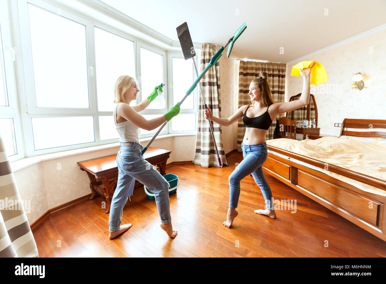 Two women play during the cleaning of the apartment, they are fighting ...