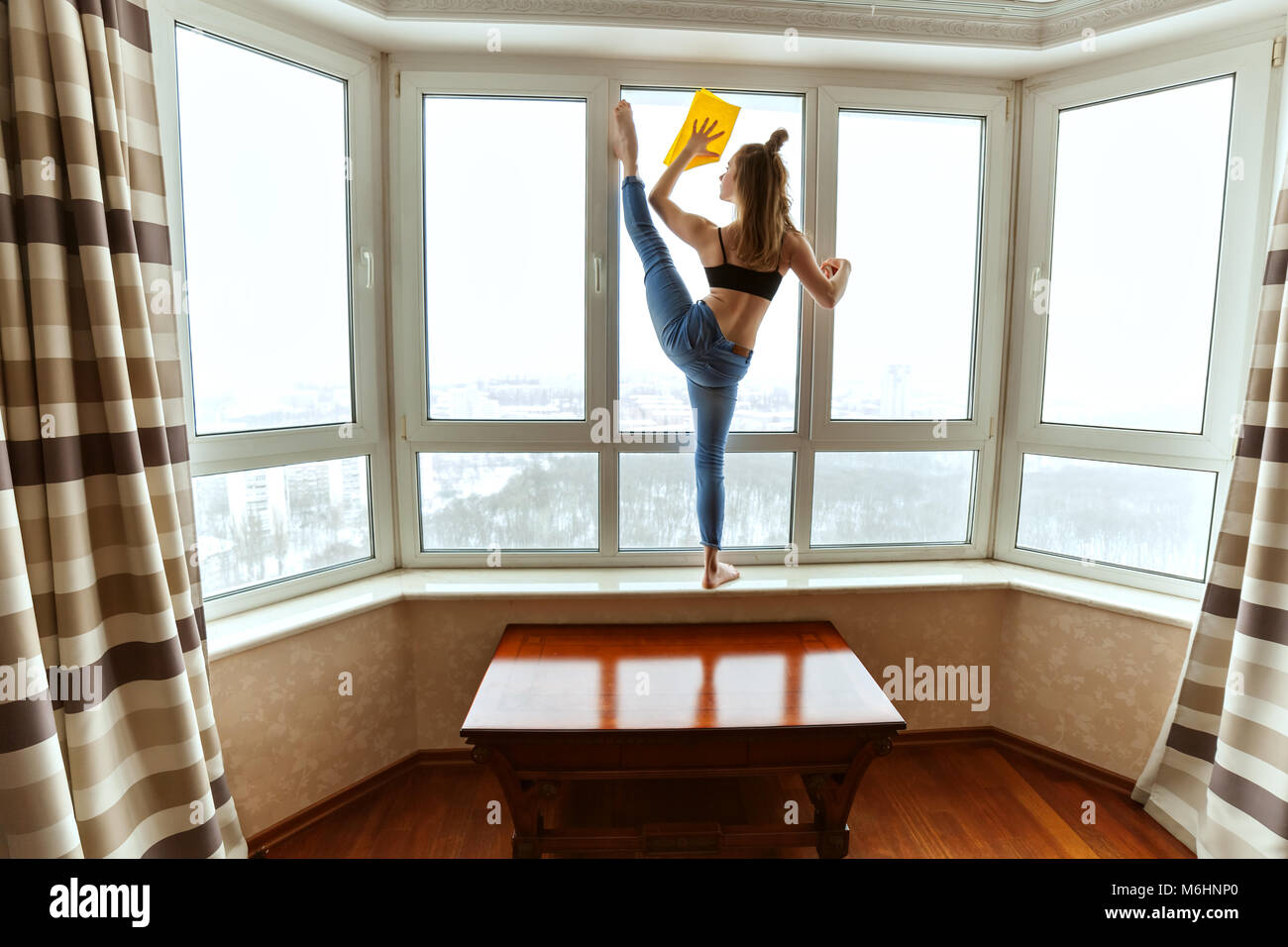 Female athlete washes windows, she is standing on one leg Stock Photo ...