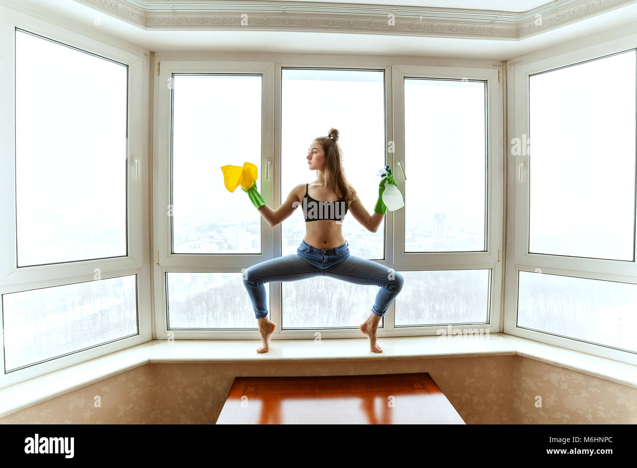 Woman gymnast washes windows and trains, sports during house cleaning ...