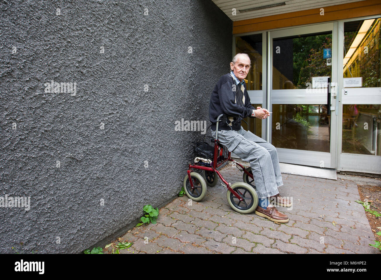 An old man with a walker takes a smoke break, Upplands Väsby, Sweden ...