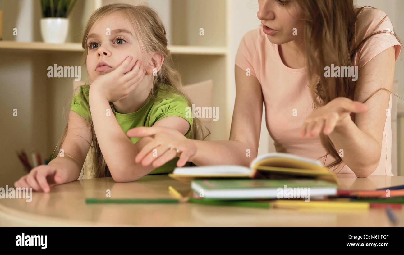 Annoyed woman hopelessly teaching little girl, naughty daughter ...