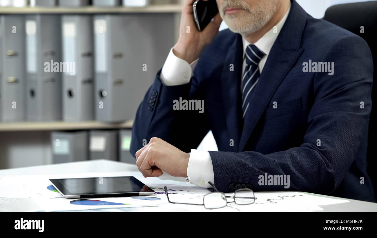 Male company director dialing, talking cell phone, tablet and glasses ...