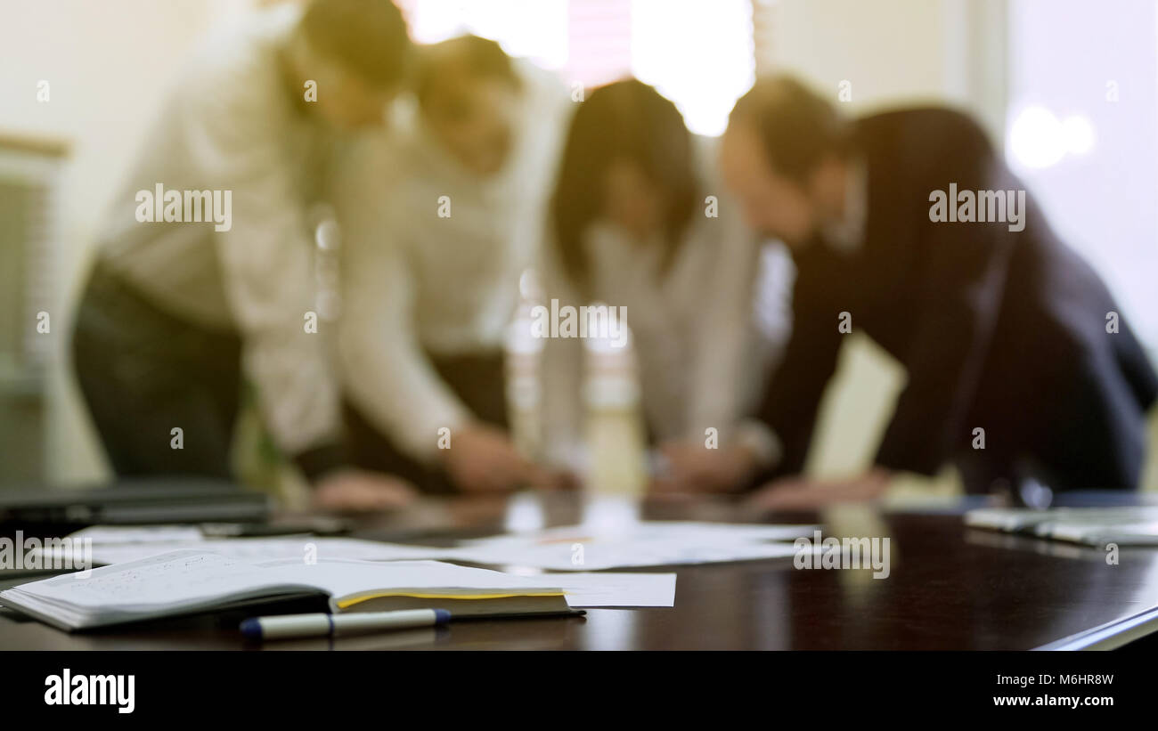 Company colleagues discussing report papers at business meeting ...