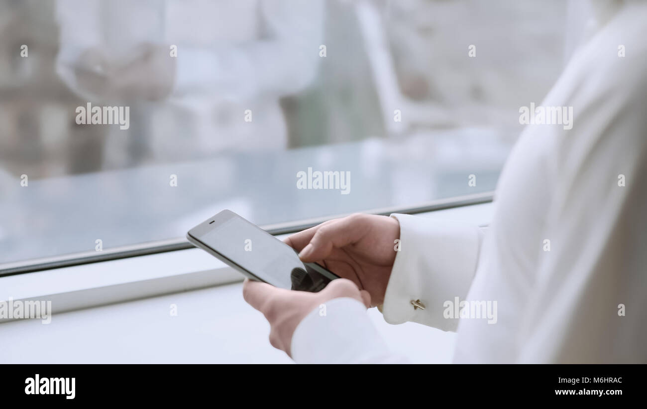 Male boss scrolling touchscreen on smartphone, readings news, window ...