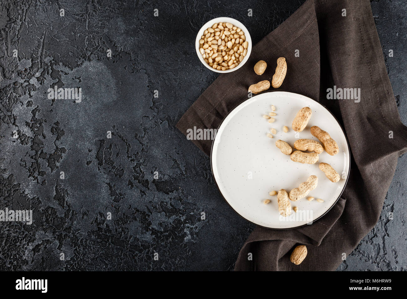 Peanuts in nutshell on a white plate with napkin on black background ...