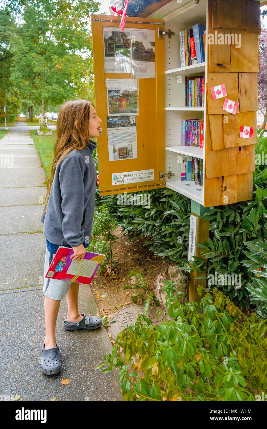 Long haired boy using little free library book box Stock Photo - Alamy