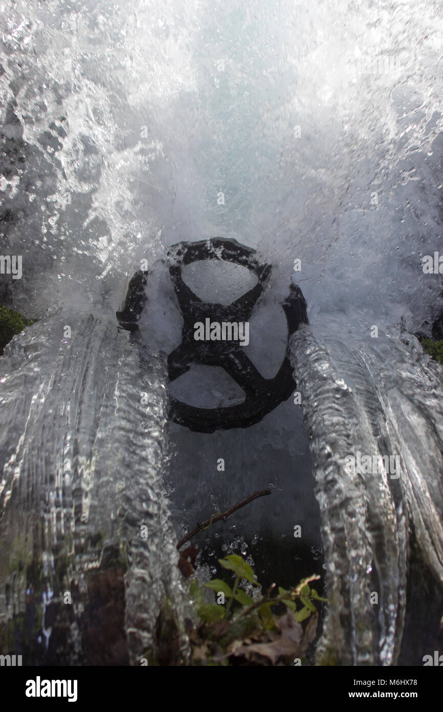 Power of water. Water from a small waterfall flows trough a big iron ...