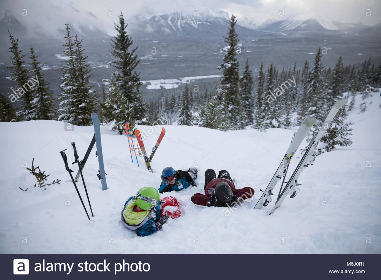 Family skiers relaxing, laying on snowy mountain Stock Photo - Alamy