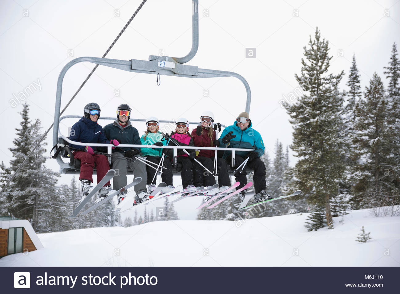 Portrait smiling family and friend skiers riding chair lift at ski ...