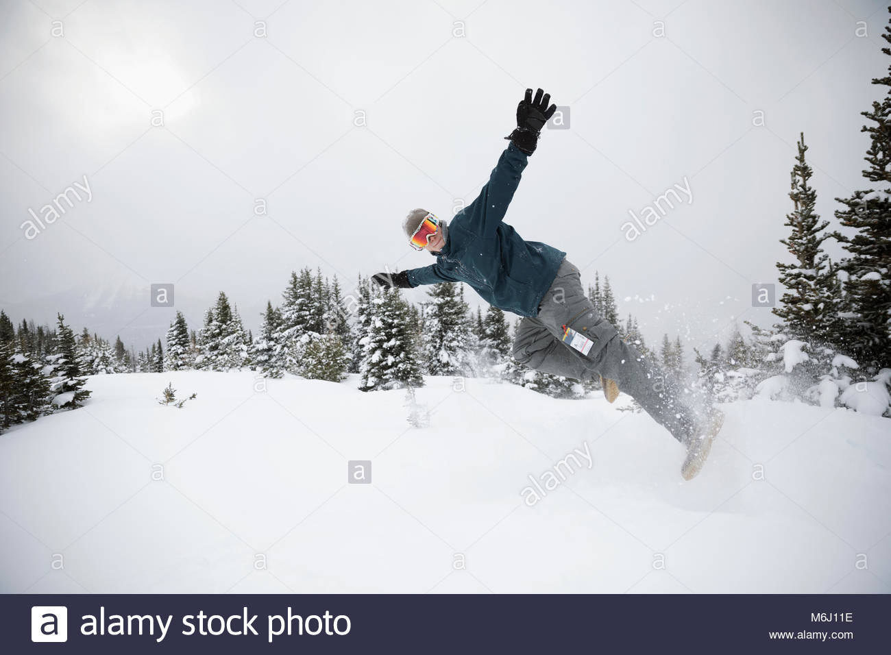 Portrait playful young man jumping in snow Stock Photo - Alamy