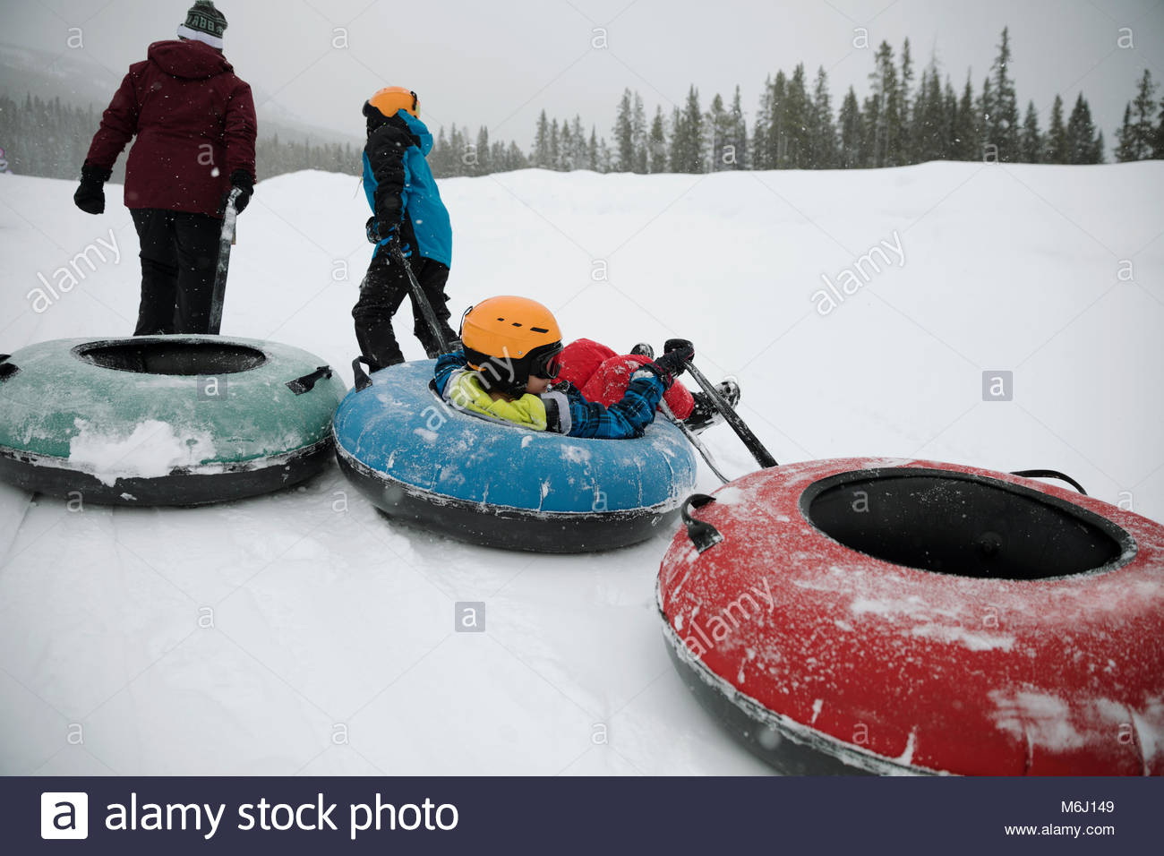 Boy pulling brother in inner tube in snow at tube park Stock Photo - Alamy