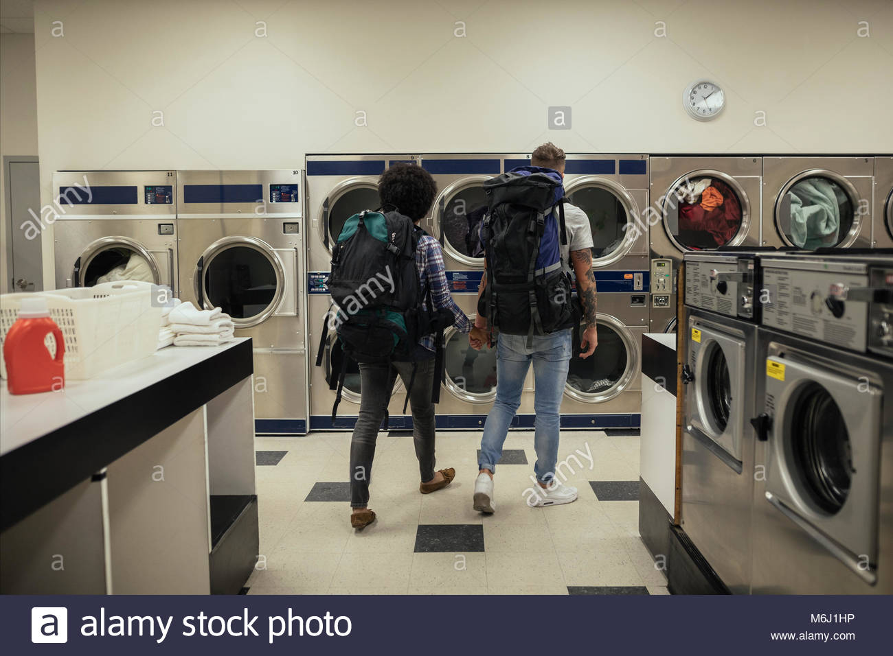 Young couple backpackers doing laundry at laundromat Stock Photo - Alamy
