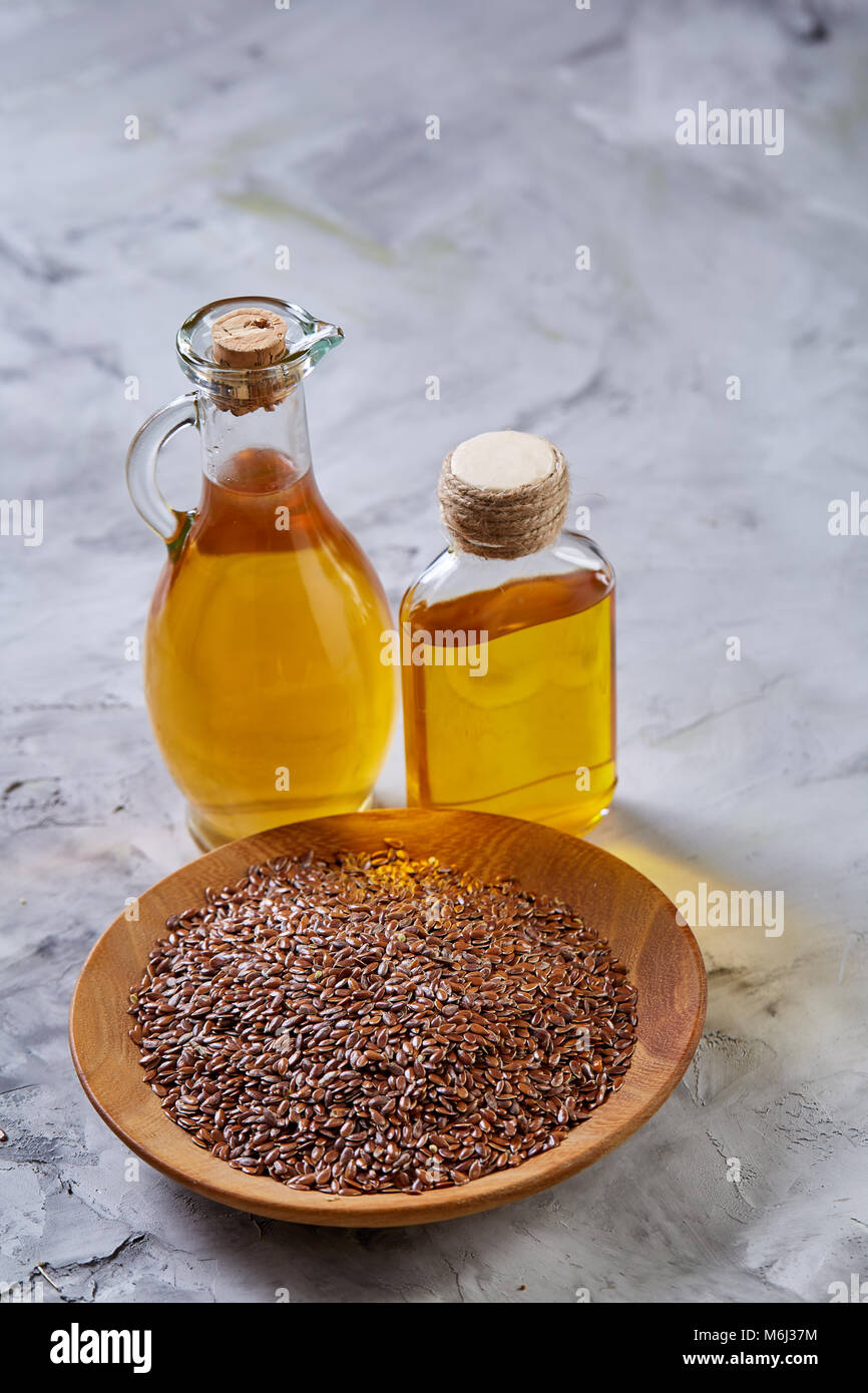 Brown flax seeds in wooden plate and flaxseed oil in glass bottle on brown rustic wooden ...