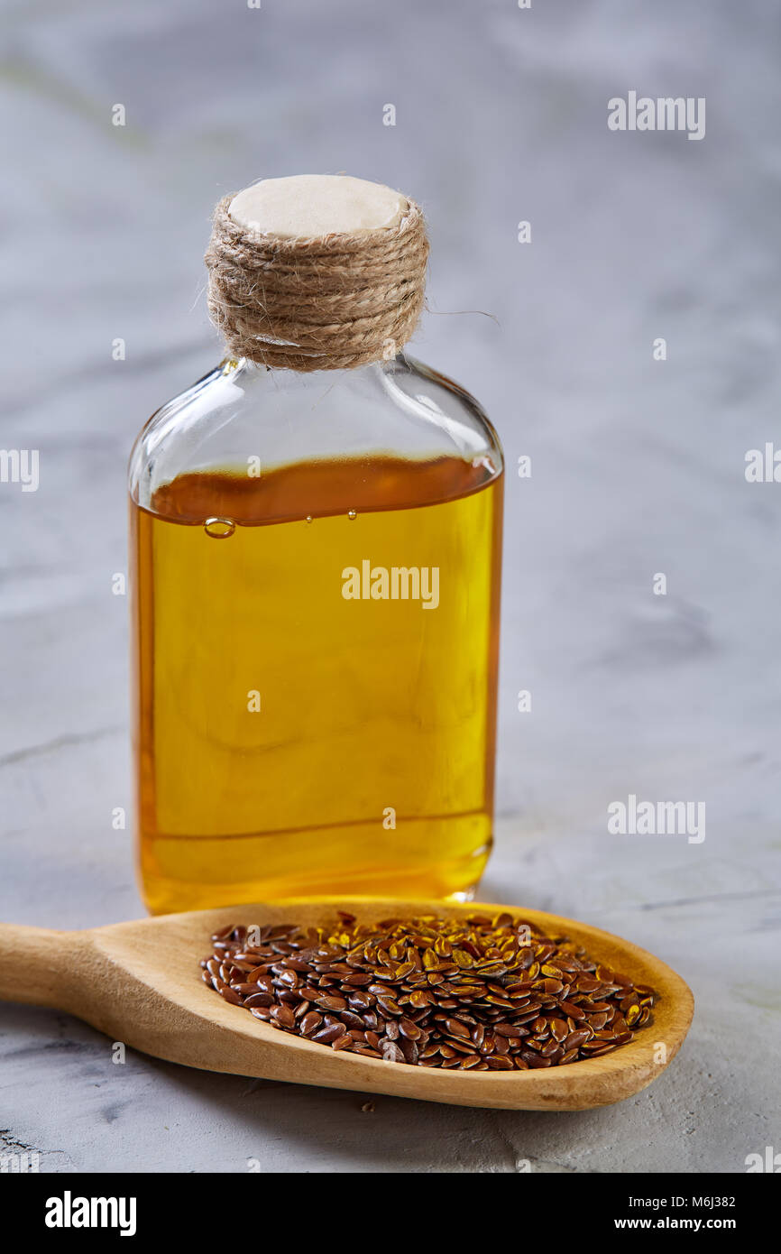 Brown flax seeds in wooden plate and flaxseed oil in glass bottle on brown rustic wooden ...