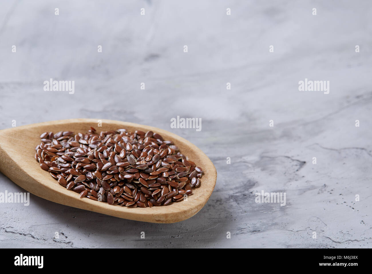 Top view close-up picture of flax seeds in wooden bowl and spoon isolated on brown rustic wooden ...