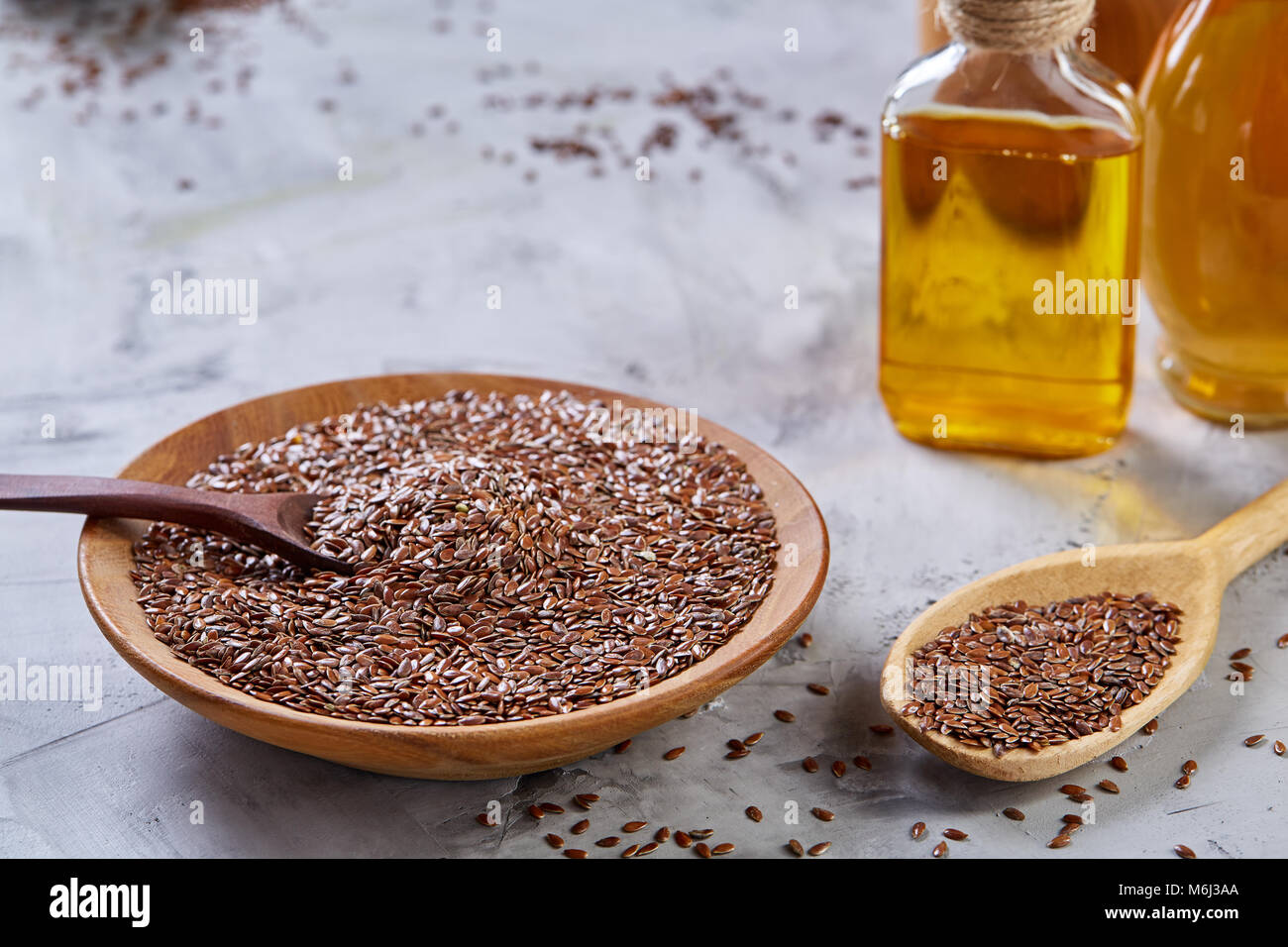 Brown flax seeds in wooden plate and flaxseed oil in glass bottle on ...