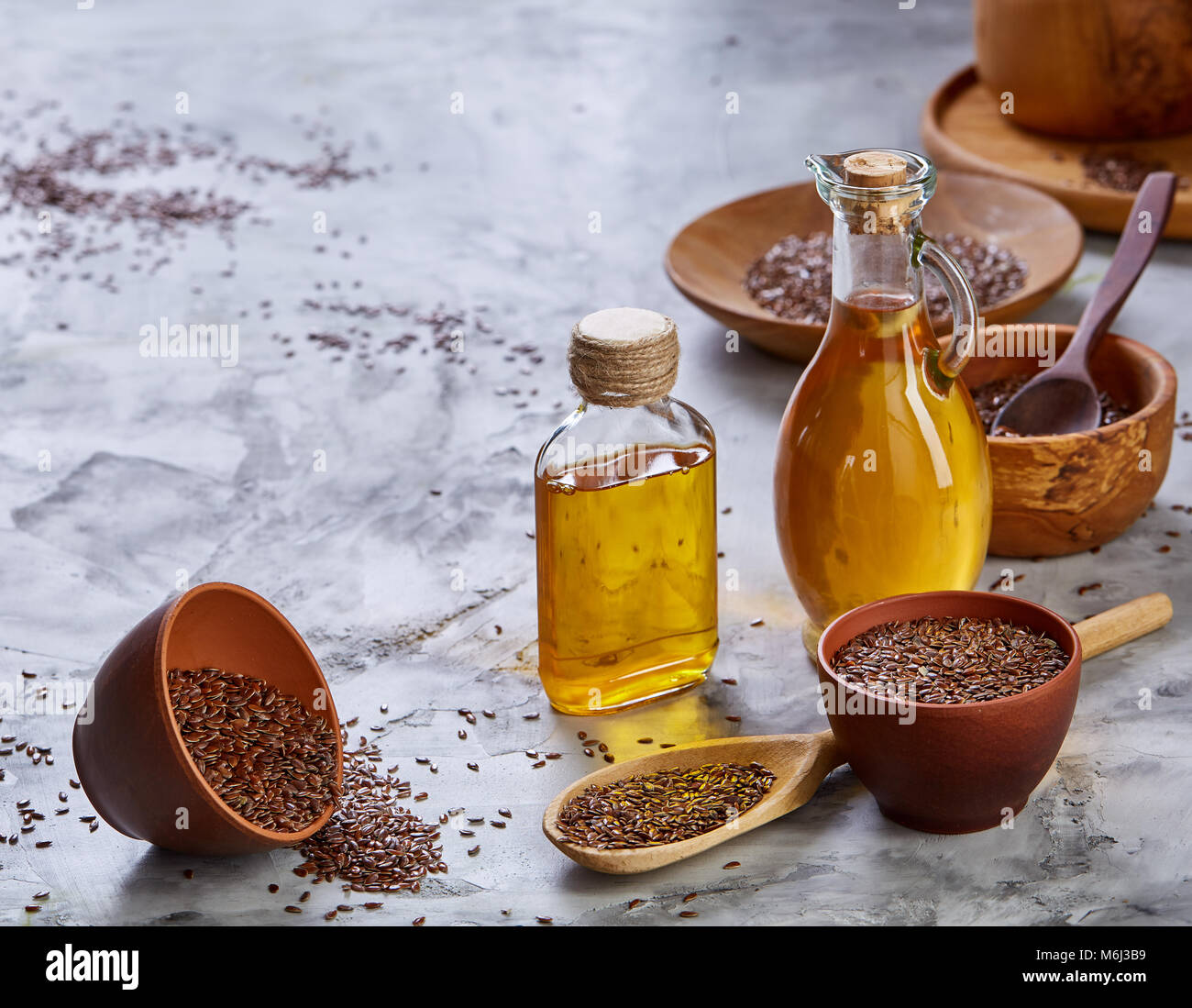 Brown flax seeds in wooden plate and flaxseed oil in glass bottle on ...