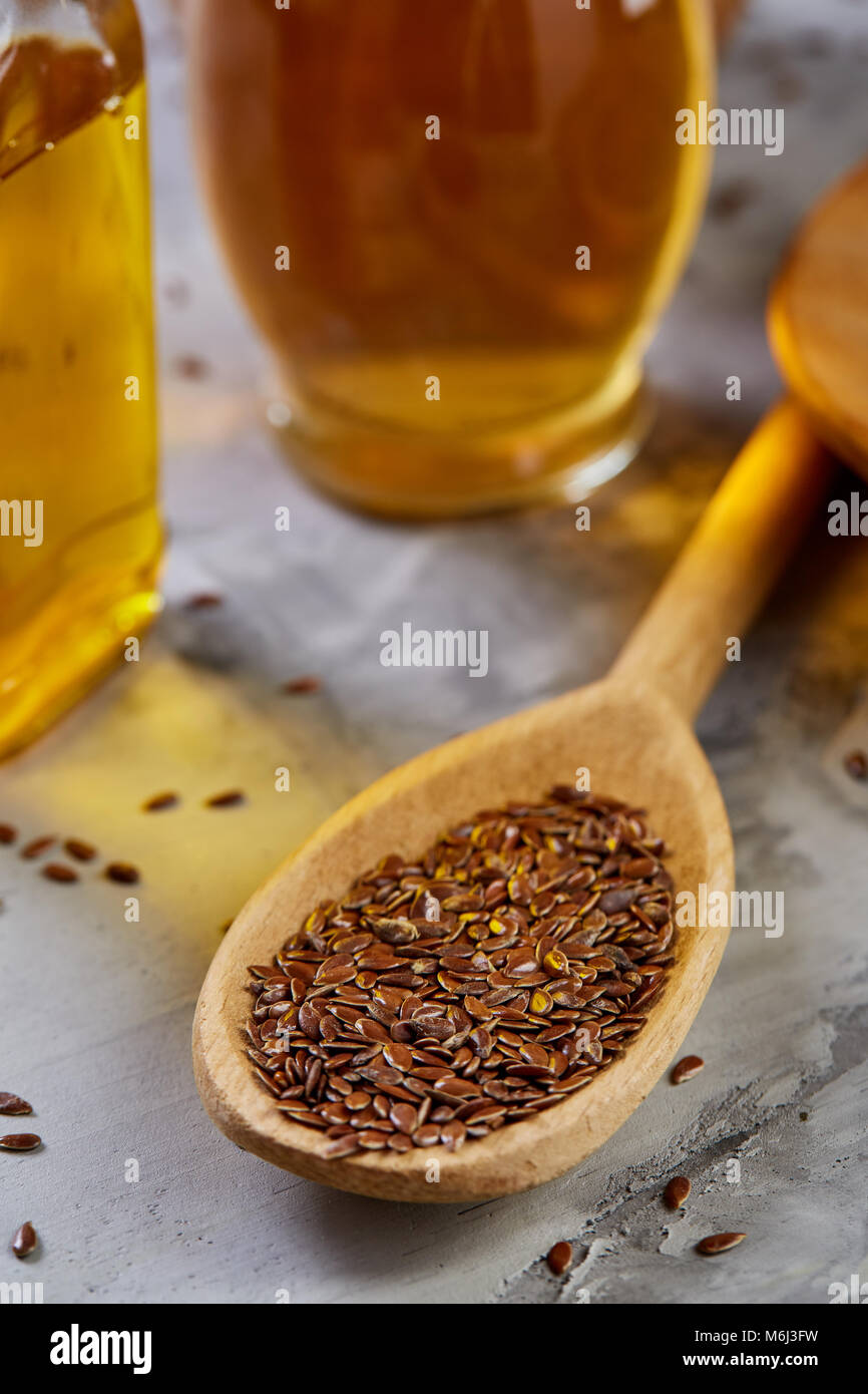 Brown flax seeds in wooden plate and flaxseed oil in glass bottle on brown rustic wooden ...