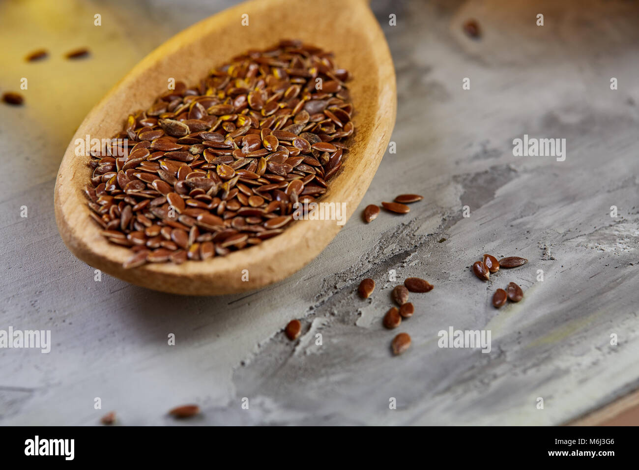Brown flax seeds in wooden plate and flaxseed oil in glass bottle on brown rustic wooden ...
