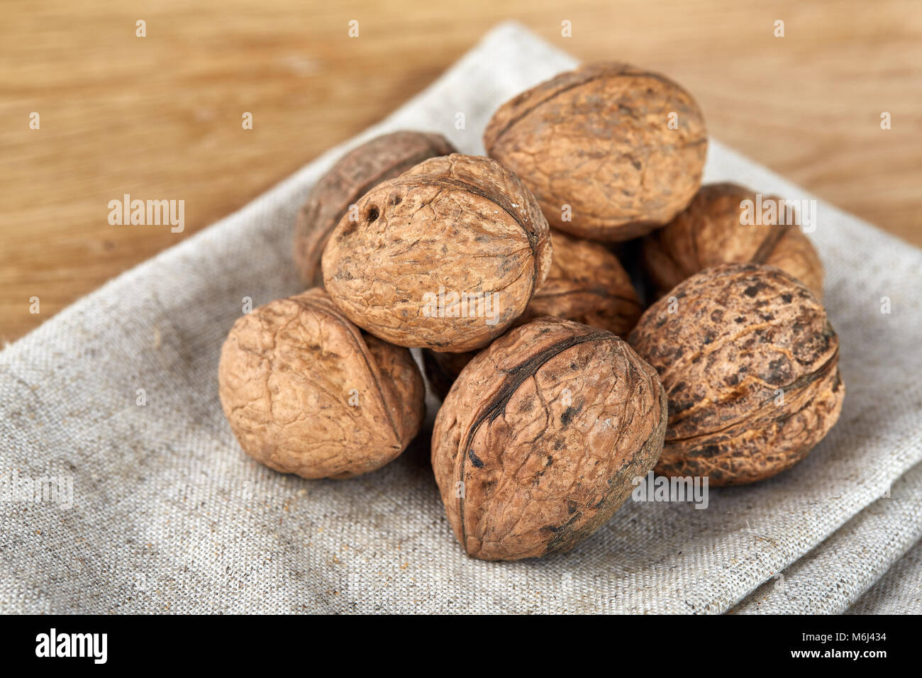 A stack of hard shells of walnuts piled together on light grey fabric ...