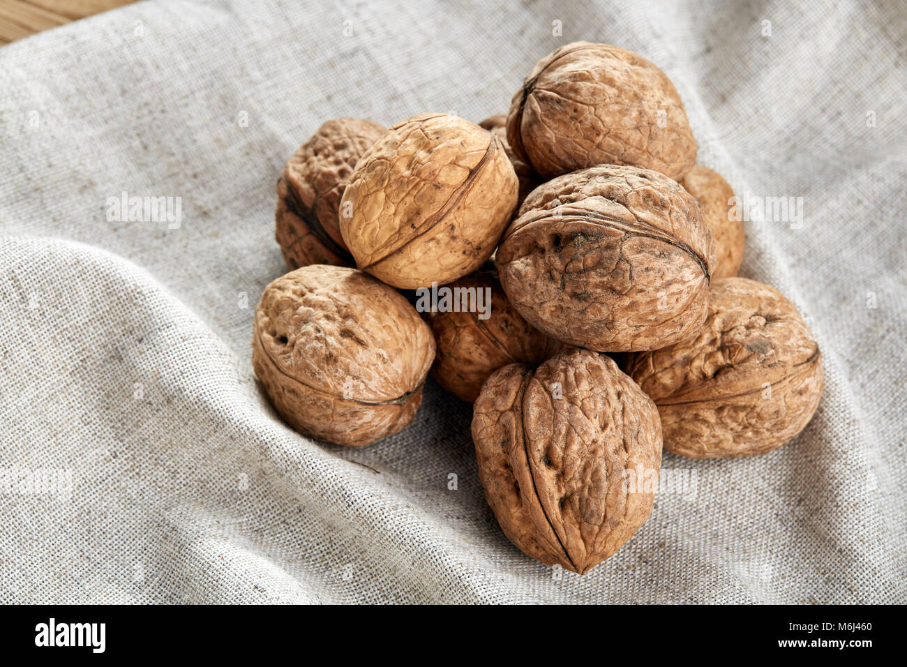 A stack of hard shells of walnuts piled together on light grey fabric ...