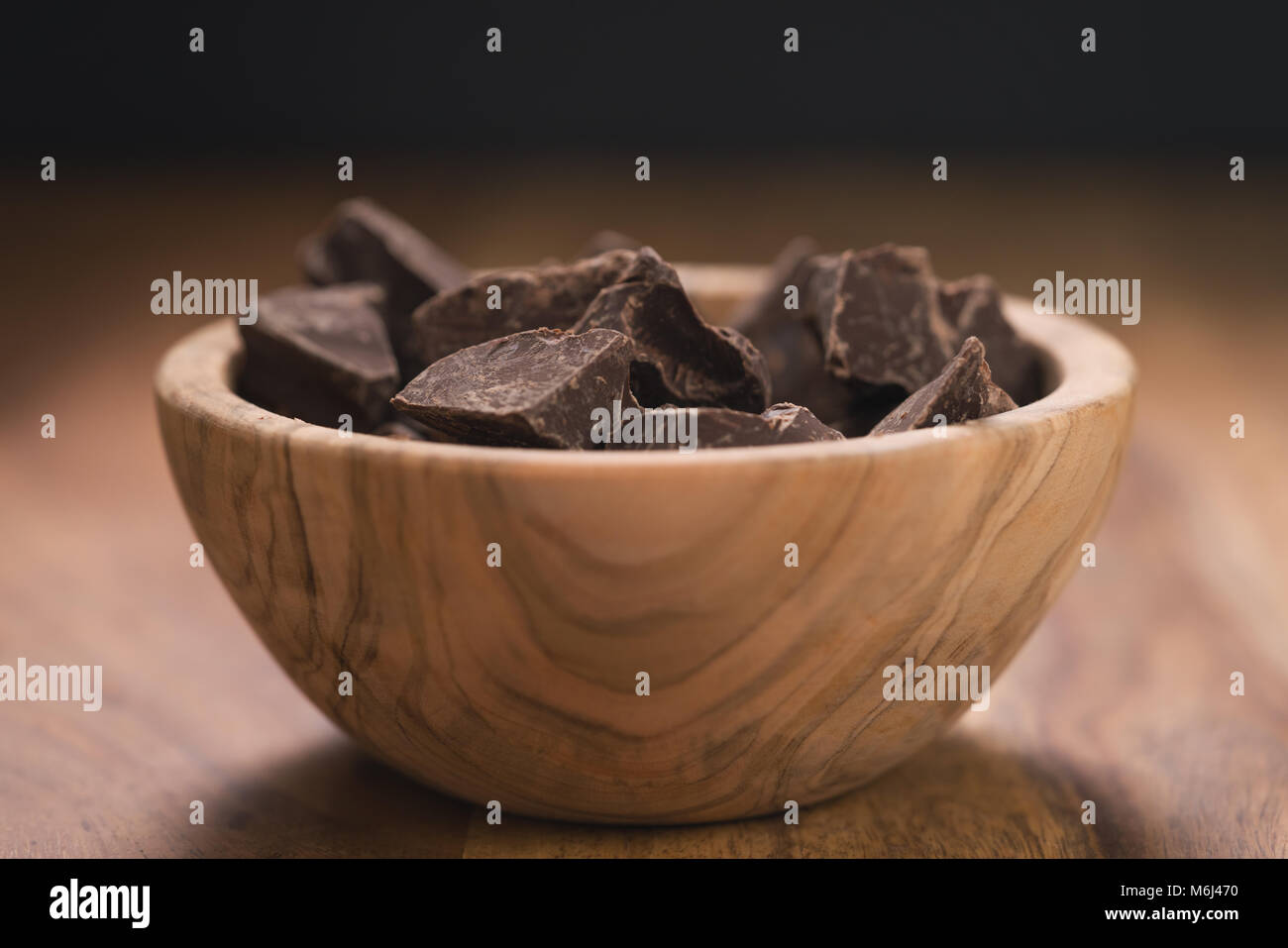 dark chocolate chunks in wood bowl on table Stock Photo - Alamy