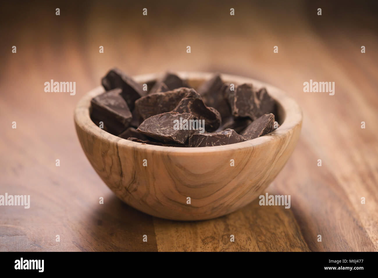 dark chocolate chunks in wood bowl on table Stock Photo - Alamy