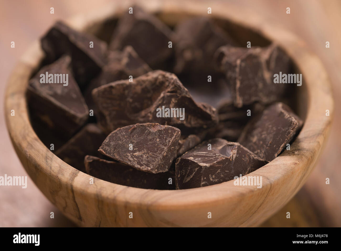 dark chocolate chunks in wood bowl on table Stock Photo - Alamy