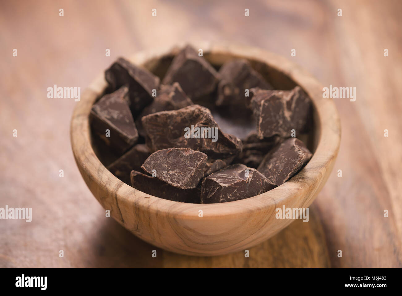 dark chocolate chunks in wood bowl on table Stock Photo - Alamy