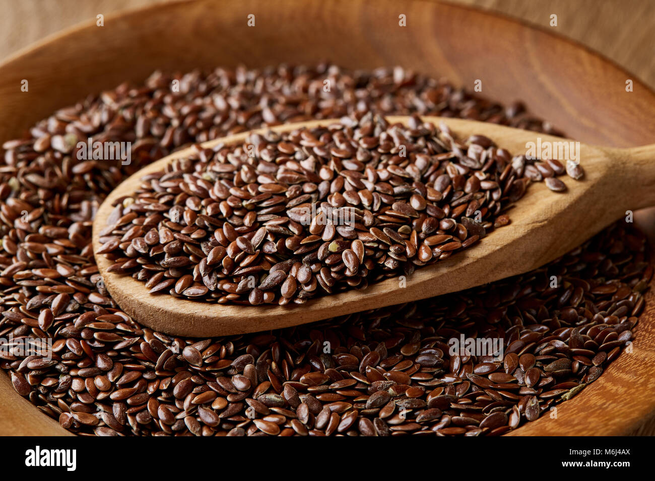 Top view, close-up picture of wooden spoon full of flax seeds over some seeds composed on rustic ...