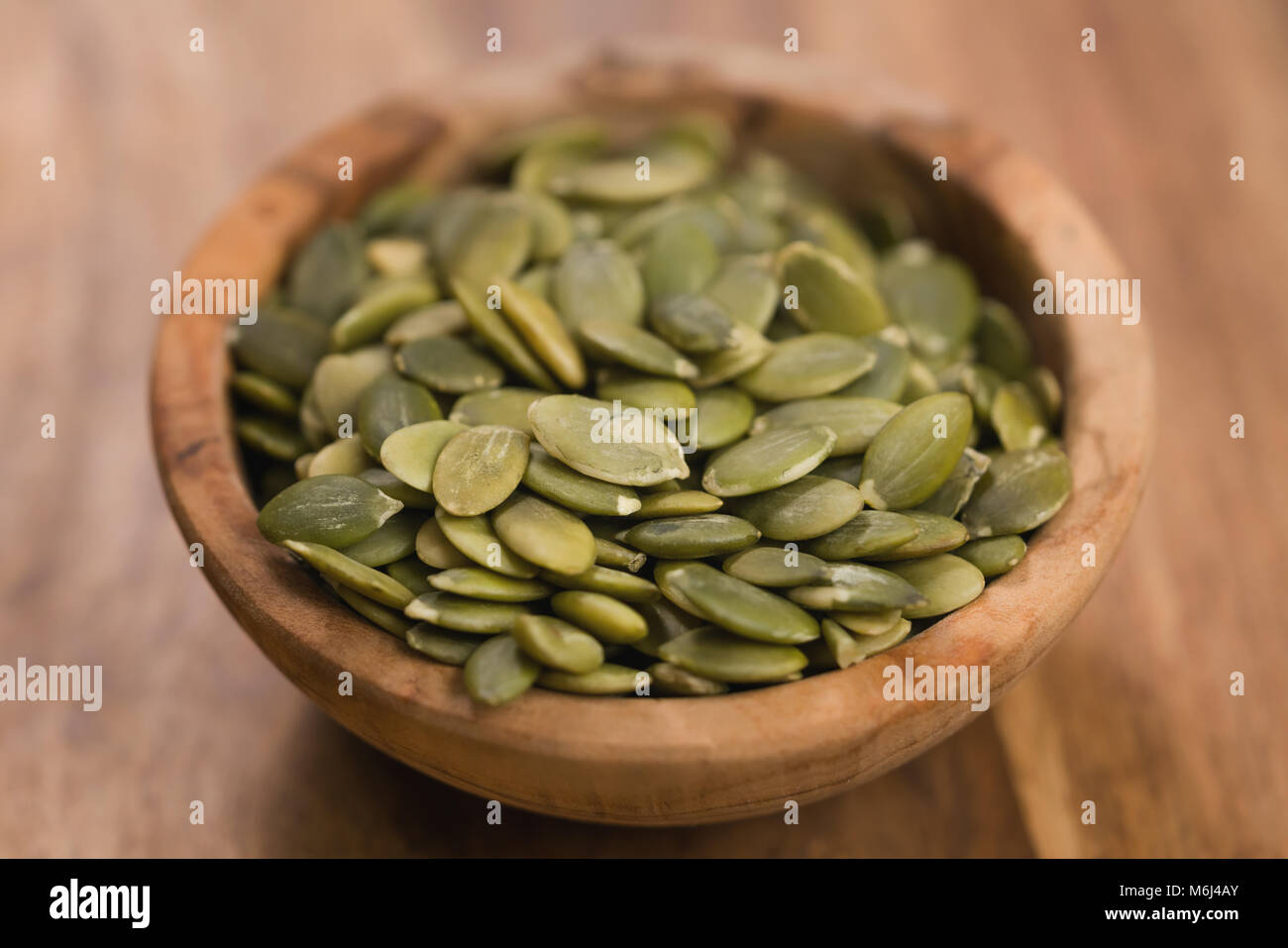green pumkin seeds in bowl on wooden table Stock Photo - Alamy
