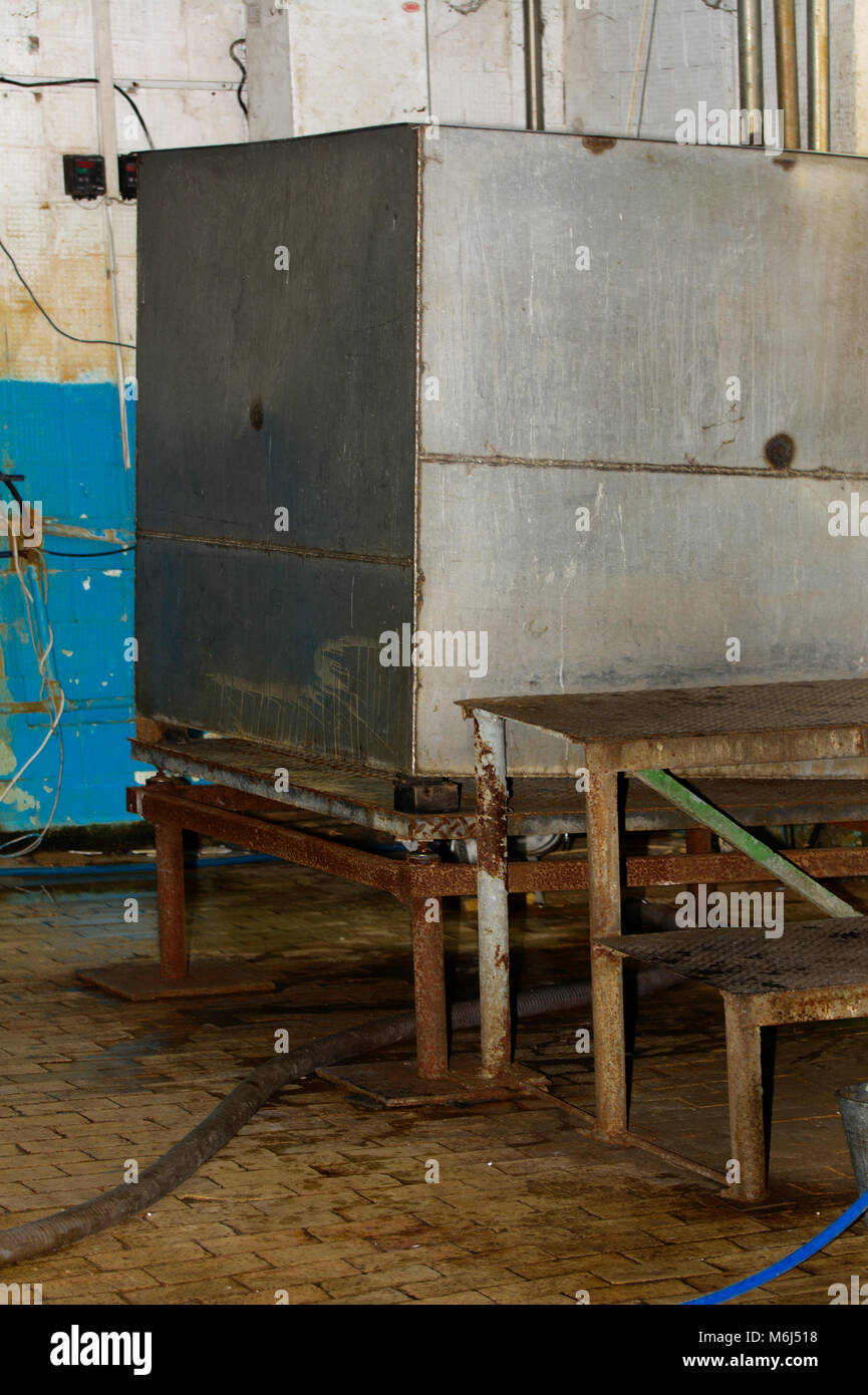 A large old dismantled and rusty tank for collecting milk in an ...
