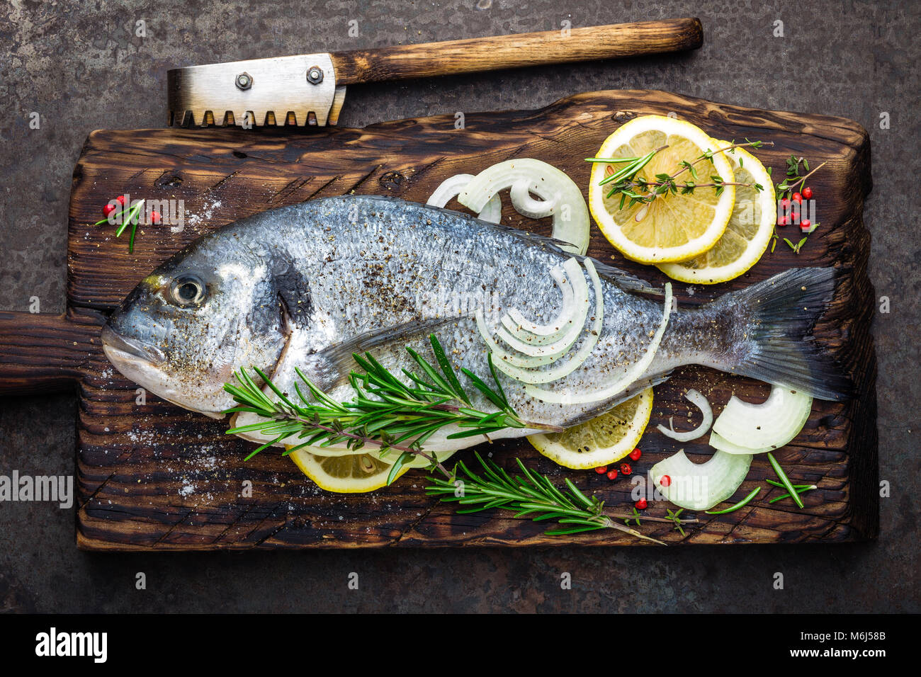 Fresh fish dorado with ingredients for cooking on wooden board. Raw sea ...