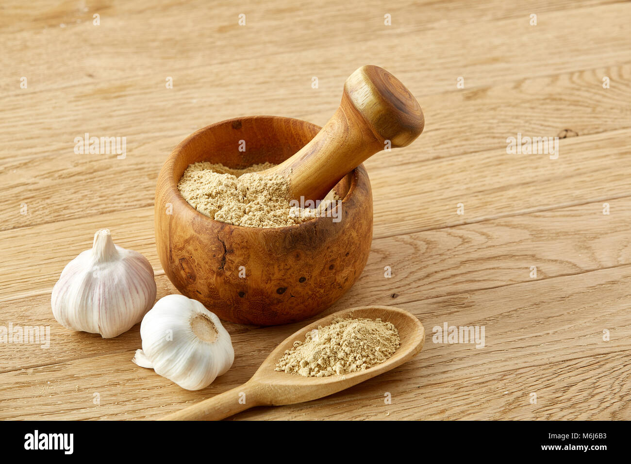 Wooden mortar and pestle with garlic and grind spices on rustic table ...