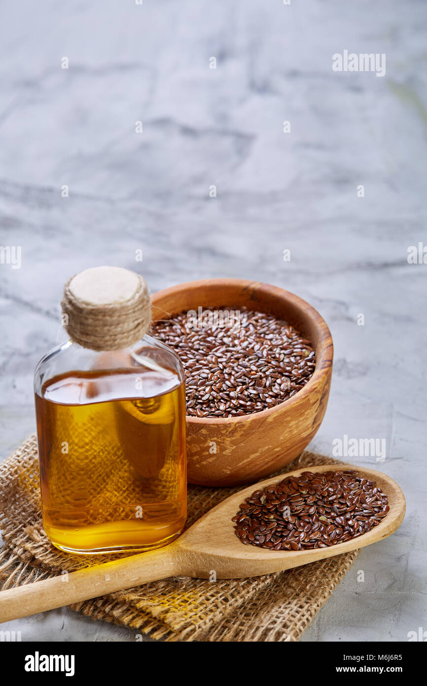 Flax seeds in bowl, wooden scoop and flaxseed oil in glass bottle over ...