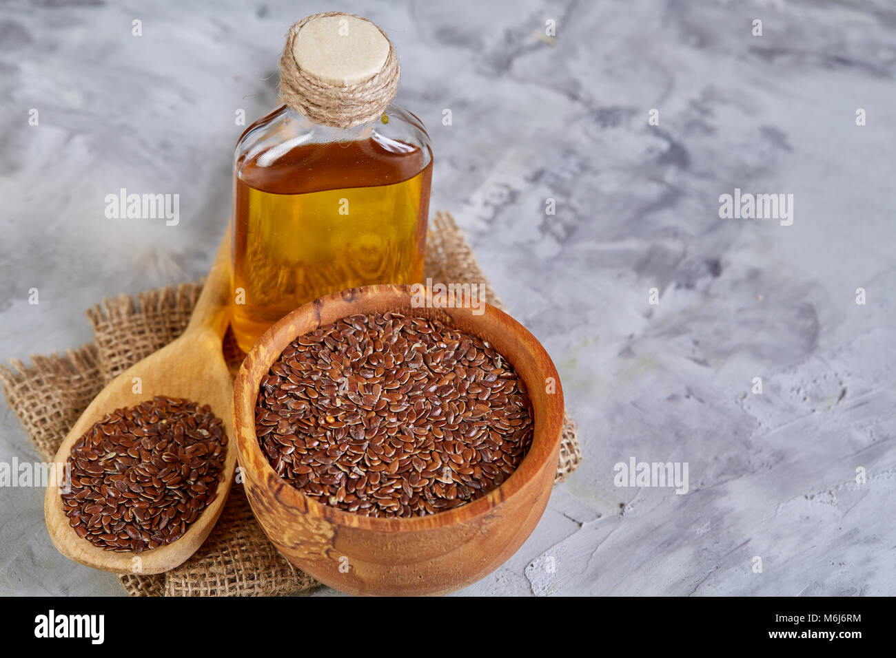 Flax seeds in bowl, wooden scoop and flaxseed oil in glass bottle over ...