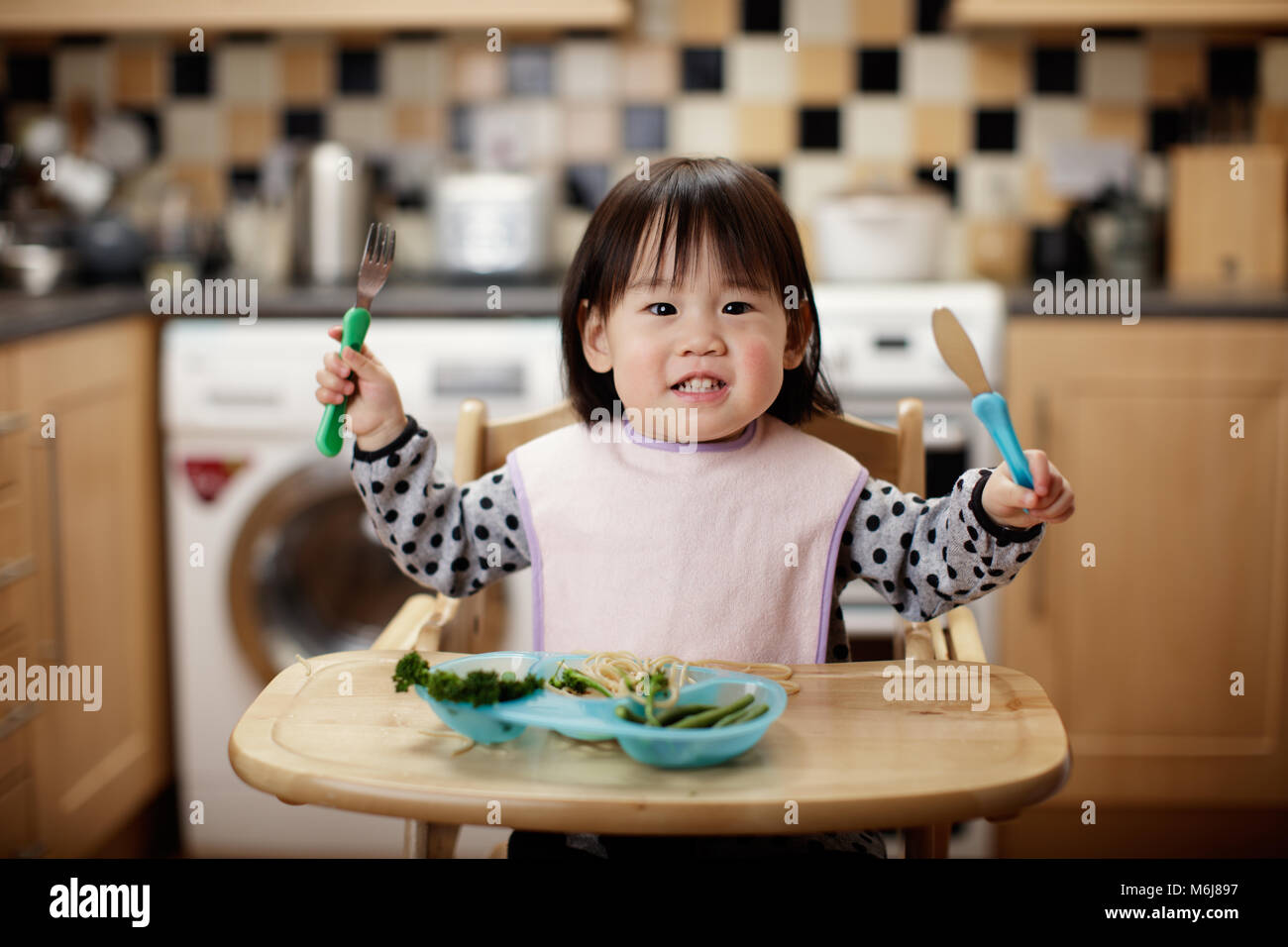 Baby girl eating messy at home kitchen Stock Photo - Alamy