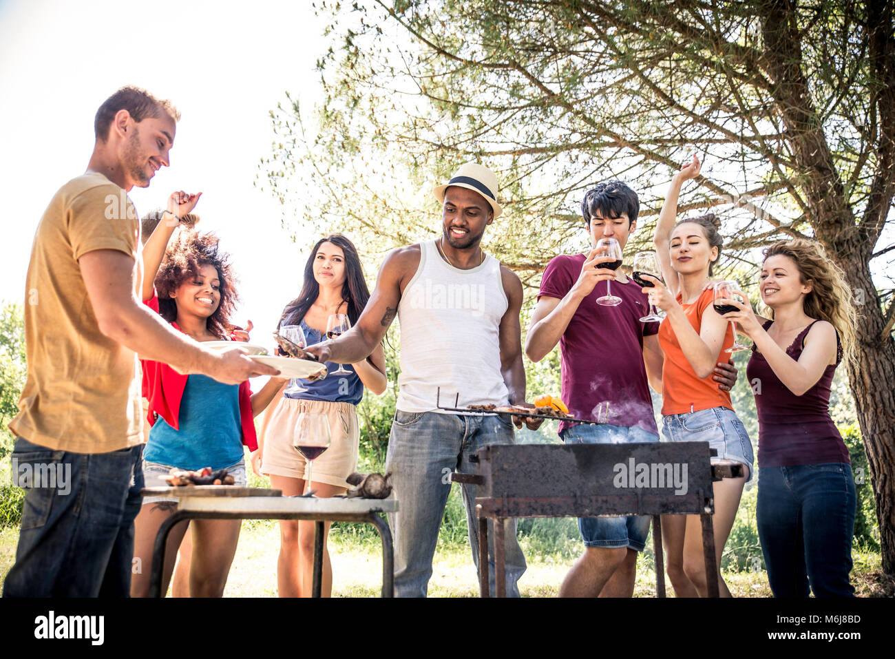 Group of friends making barbecue in the nature. Eating and sharing ...