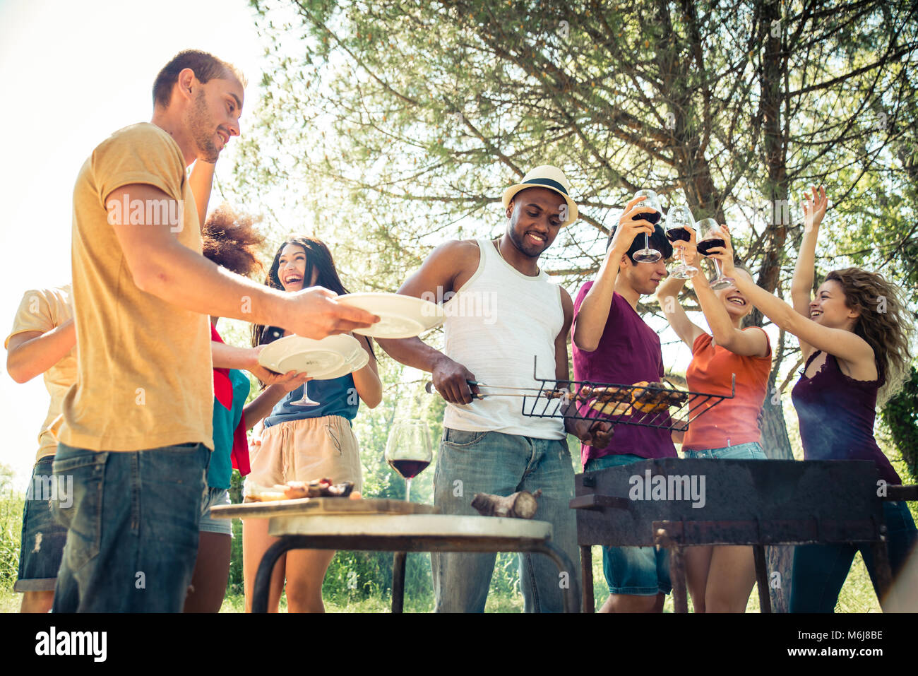 Group of friends making barbecue in the nature. Eating and sharing ...