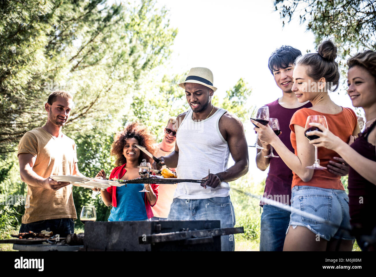 Group of friends making barbecue in the nature. Eating and sharing ...