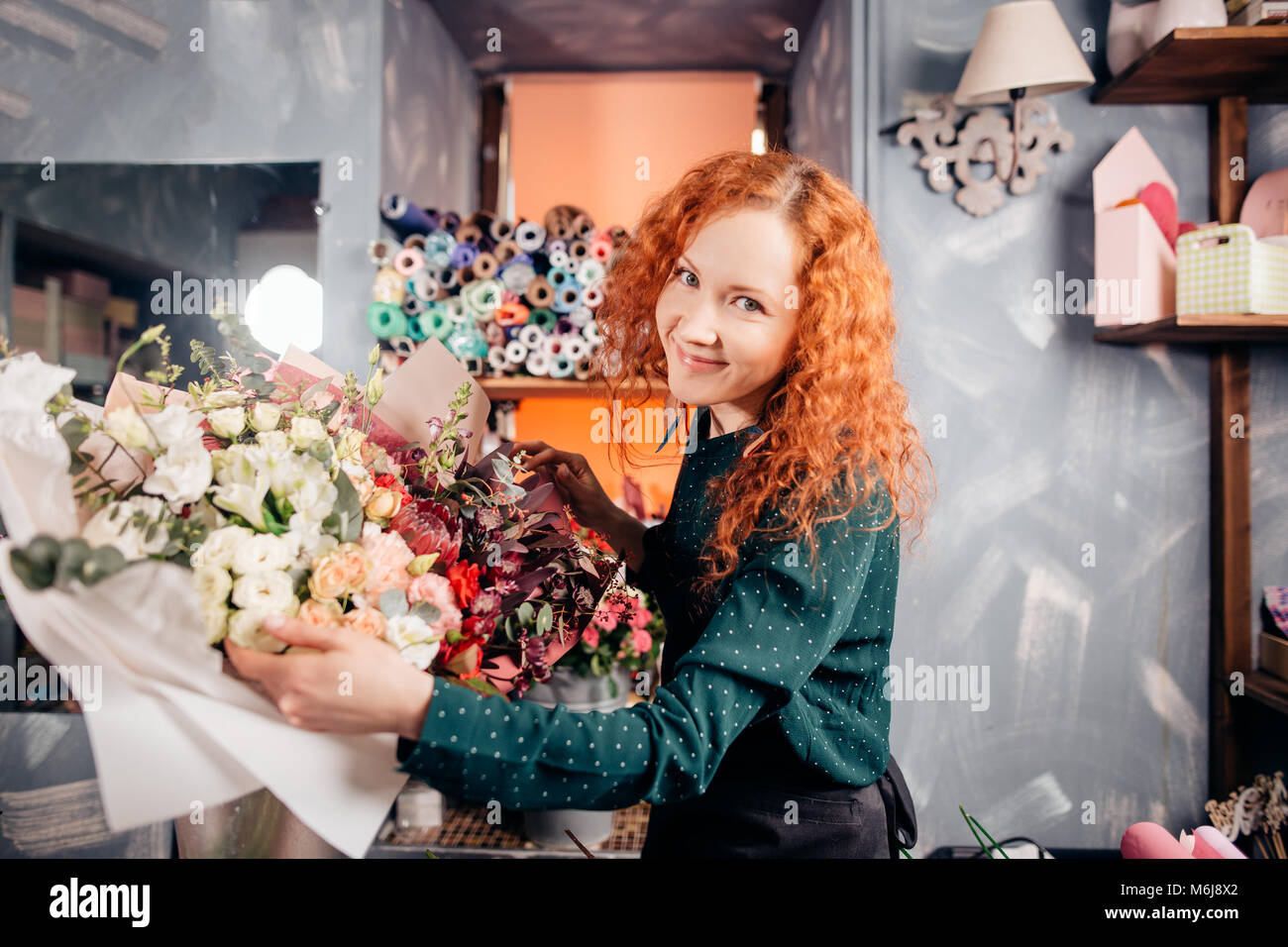 portrait of beautiful shop assistant taking two flower bouquets in ...
