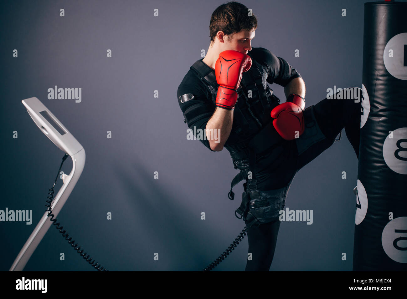 man training knee kick. A kickboxer wearing suit of electric ...