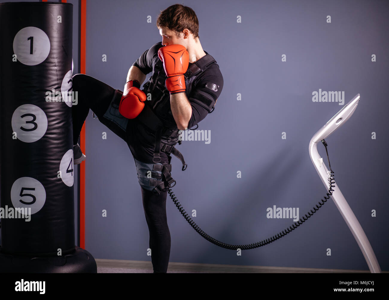 man training knee kick. A kickboxer wearing suit of electric ...