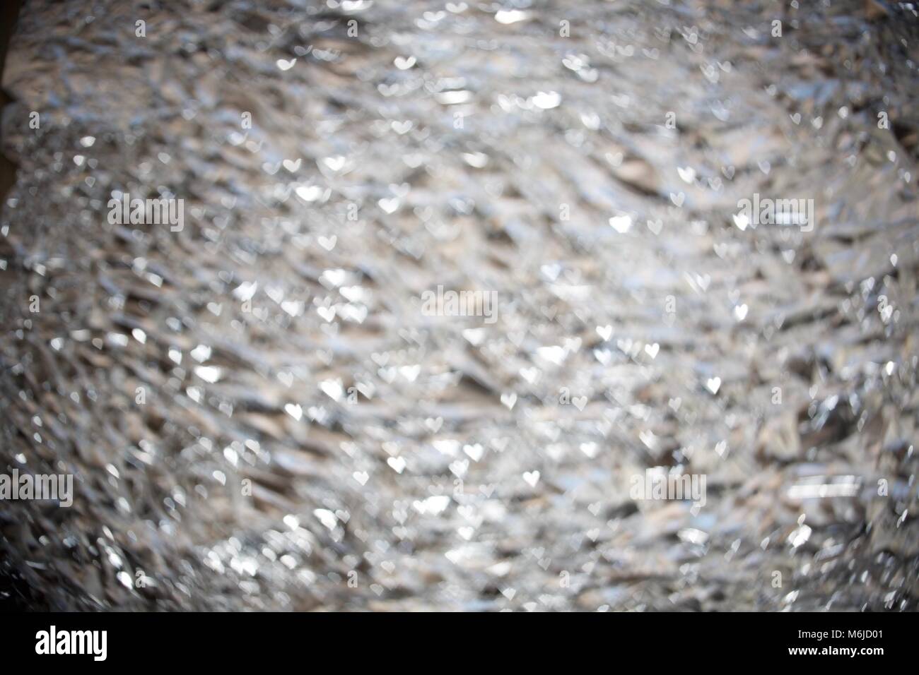 Sparkling spots of figured Bokeh - shining white hearts, metal surface ...