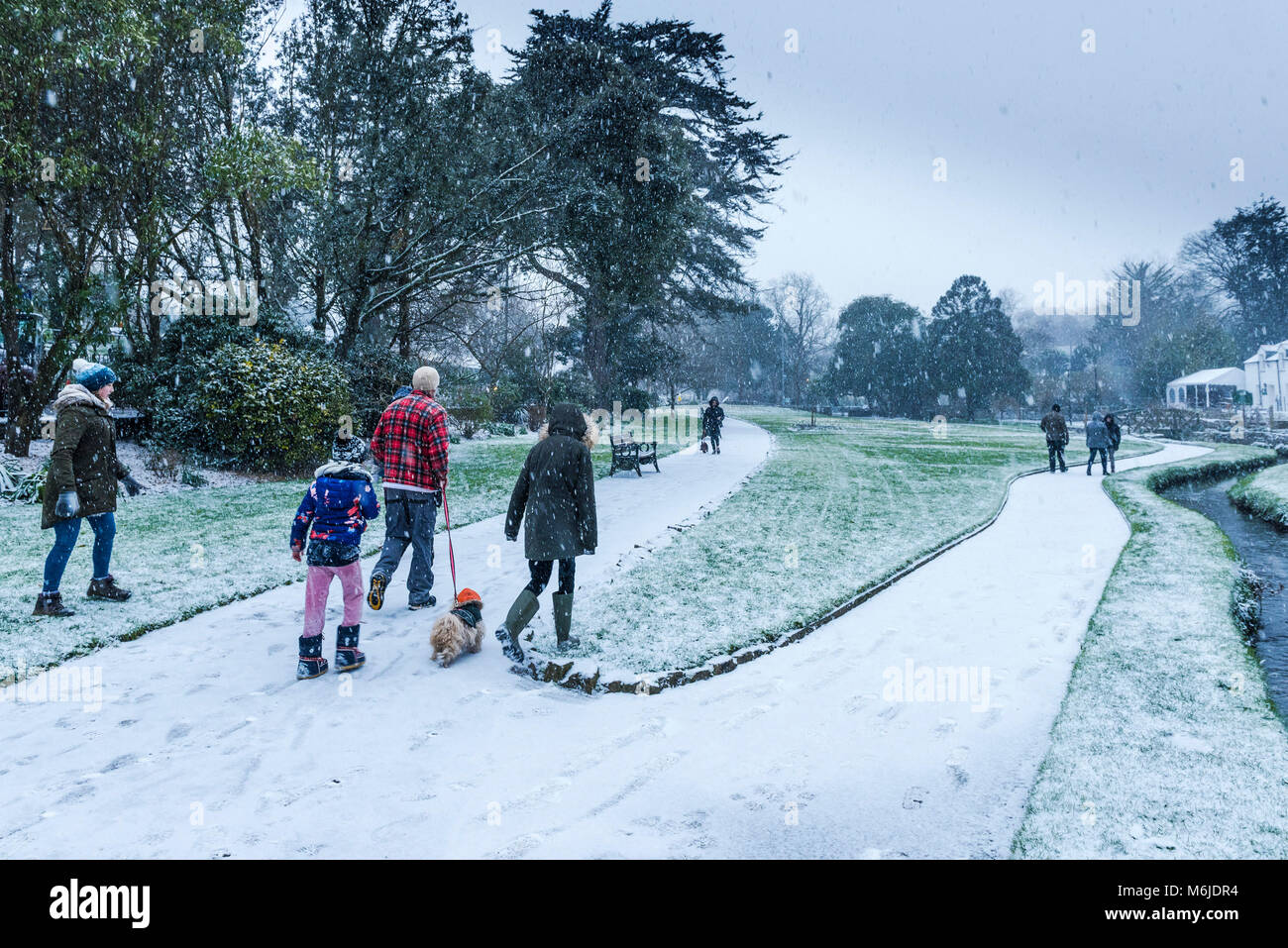 A family walking their dog through falling snow in Trenance Gardens in ...