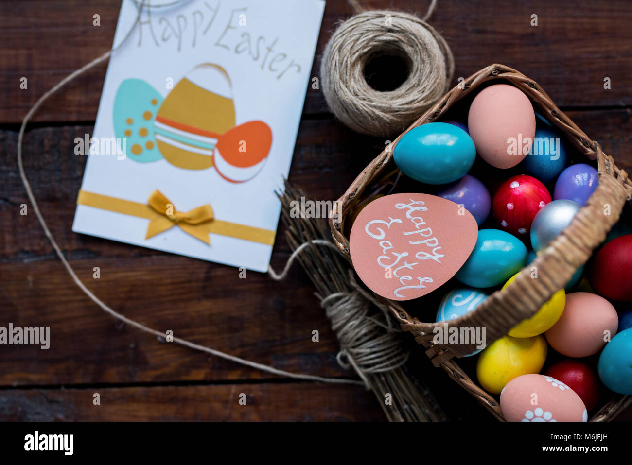 Background image of wicker basket with colorful Easter eggs in on rough wooden table with Happy ...