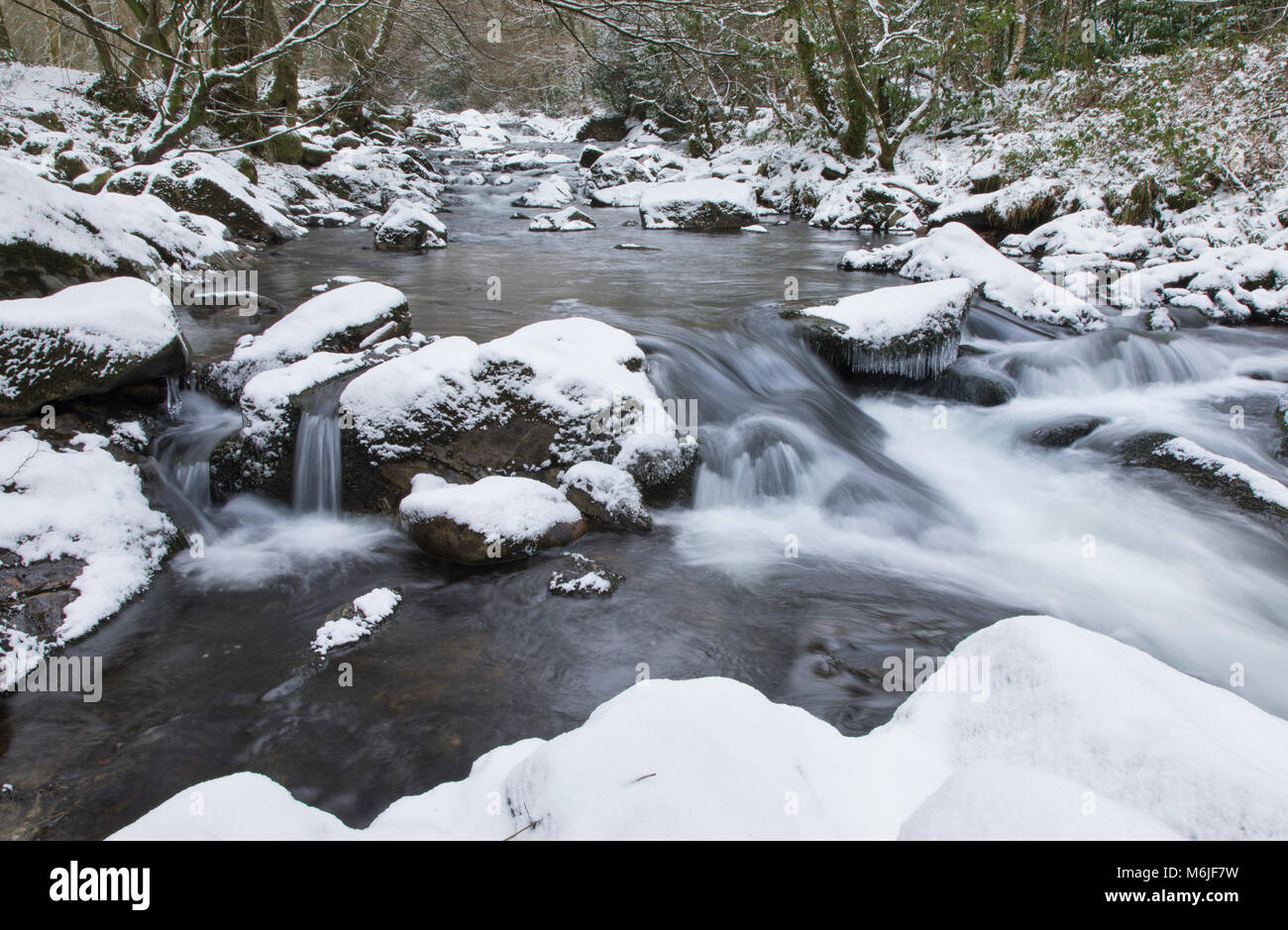 Long Exposure of water flowing down a stream surrounded by snow, River ...