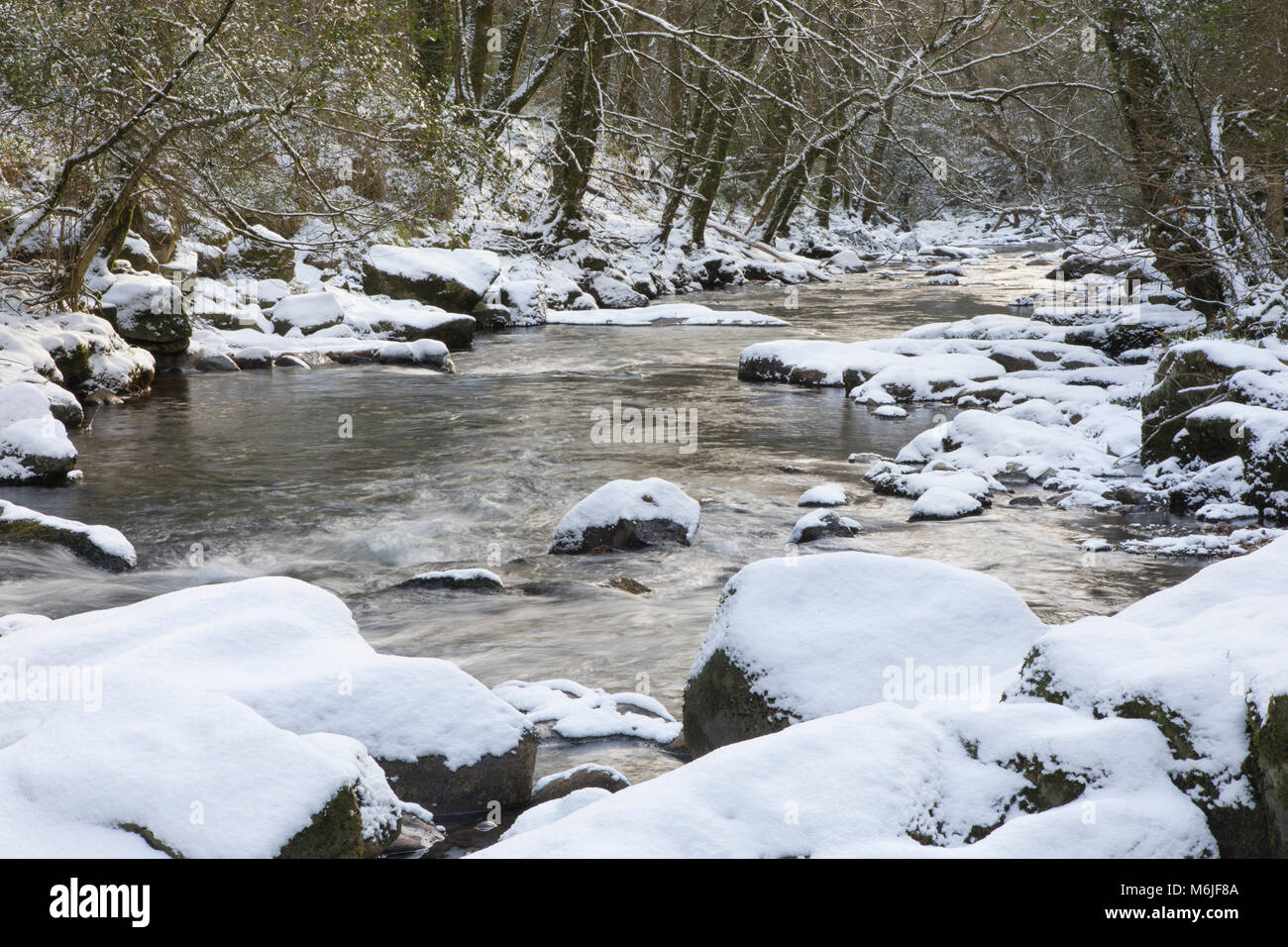 Long Exposure of water flowing down a stream surrounded by snow, River ...