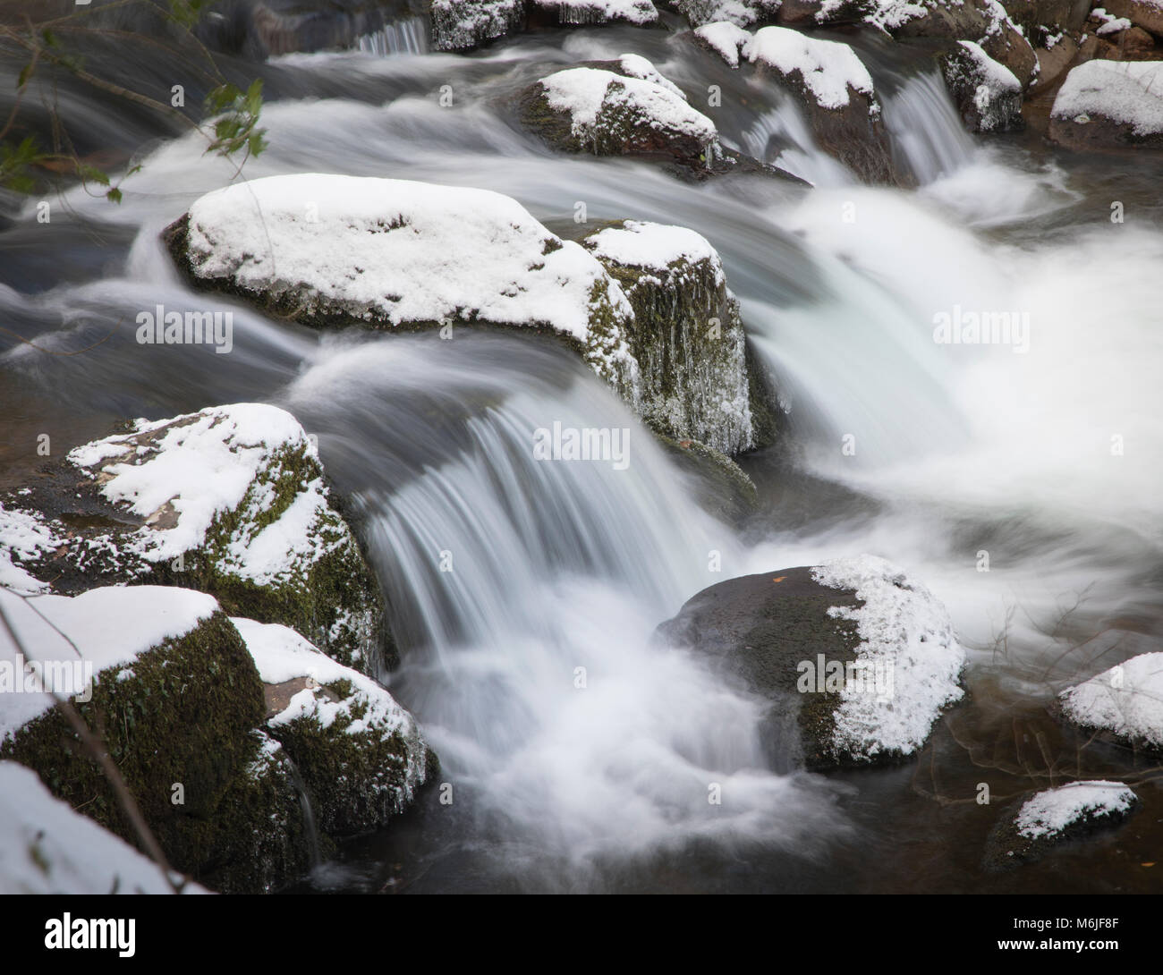Long Exposure of water flowing down a stream surrounded by snow, River ...