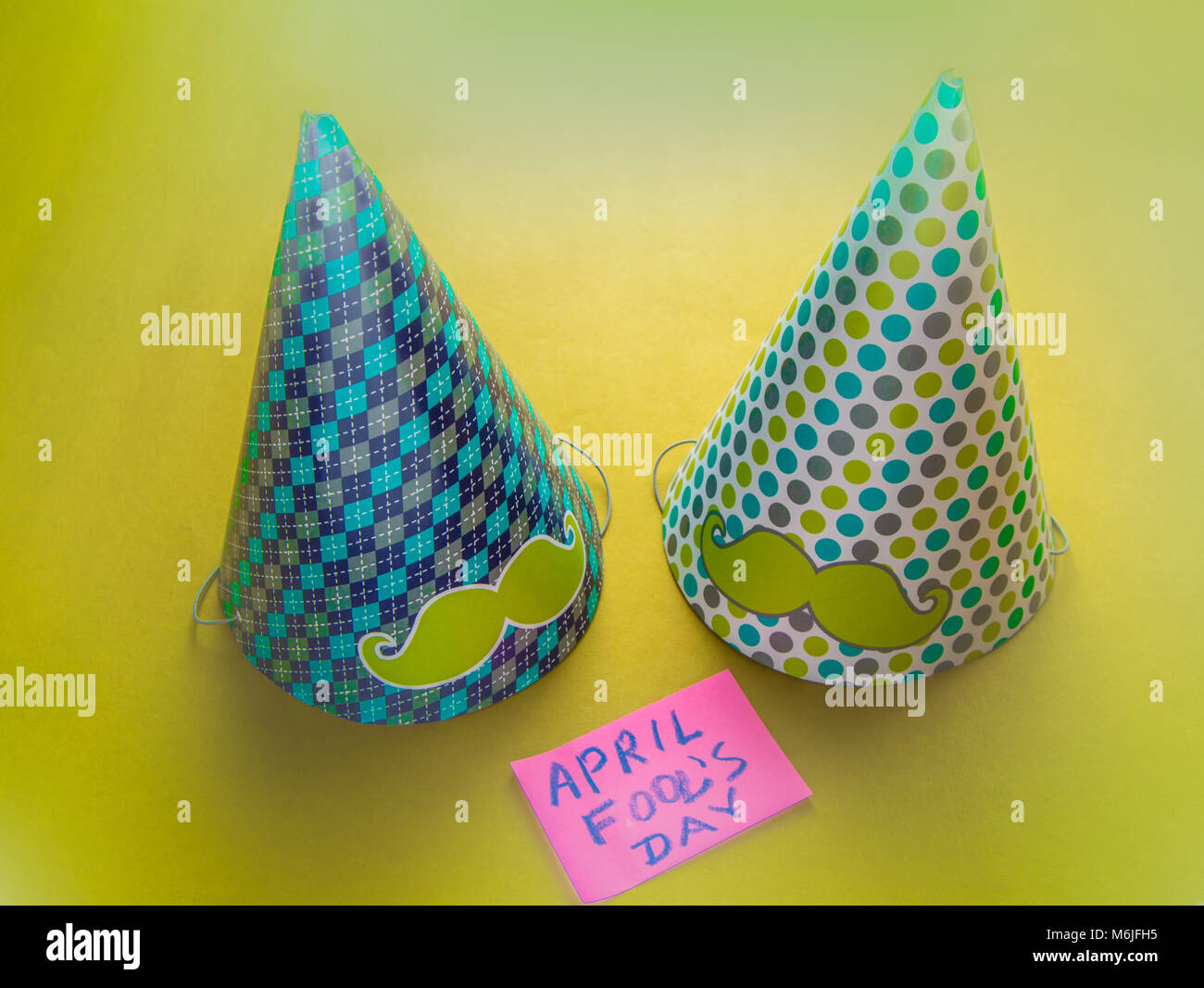 Cap, April fool's day lettering yellow background Stock Photo - Alamy